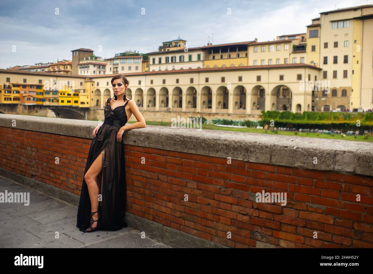 Beautiful stylish bride in a black dress stands on the embankment in ...