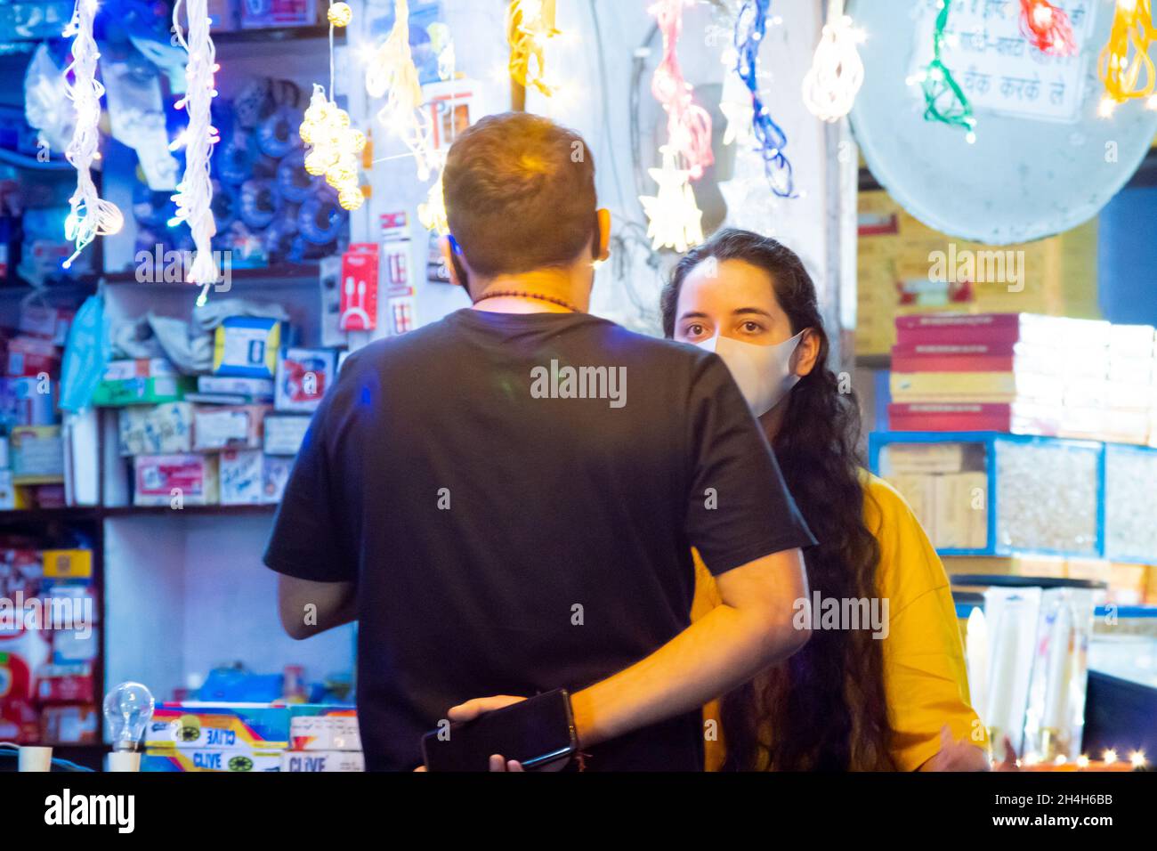 man and woman standing at a shop lit by colorful lights on the hindu ...