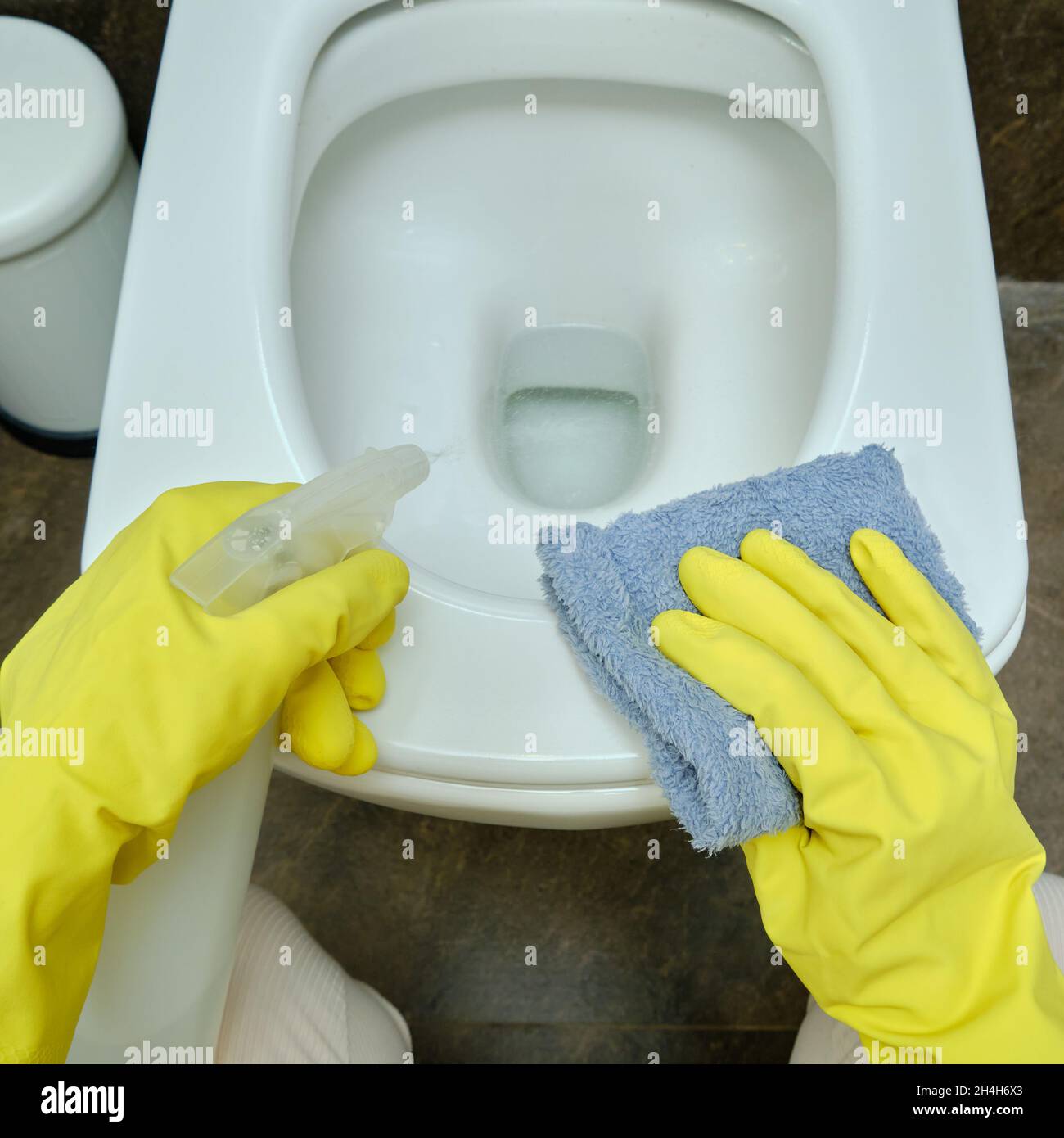 Man cleans up the bathroom by wiping the toilet bowl with a rag ...