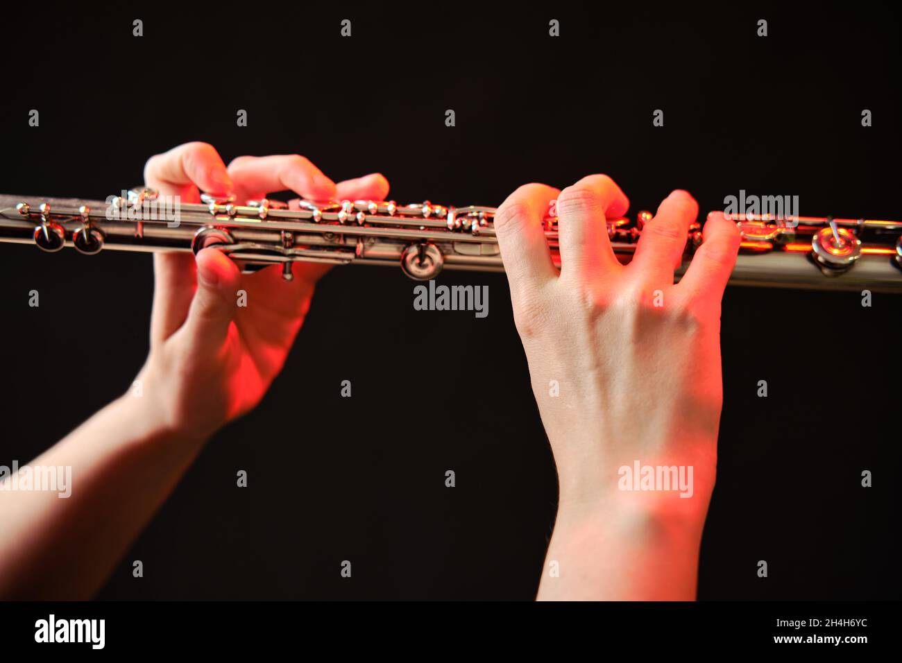 Hands of a woman musician with a flute on a studio black background ...