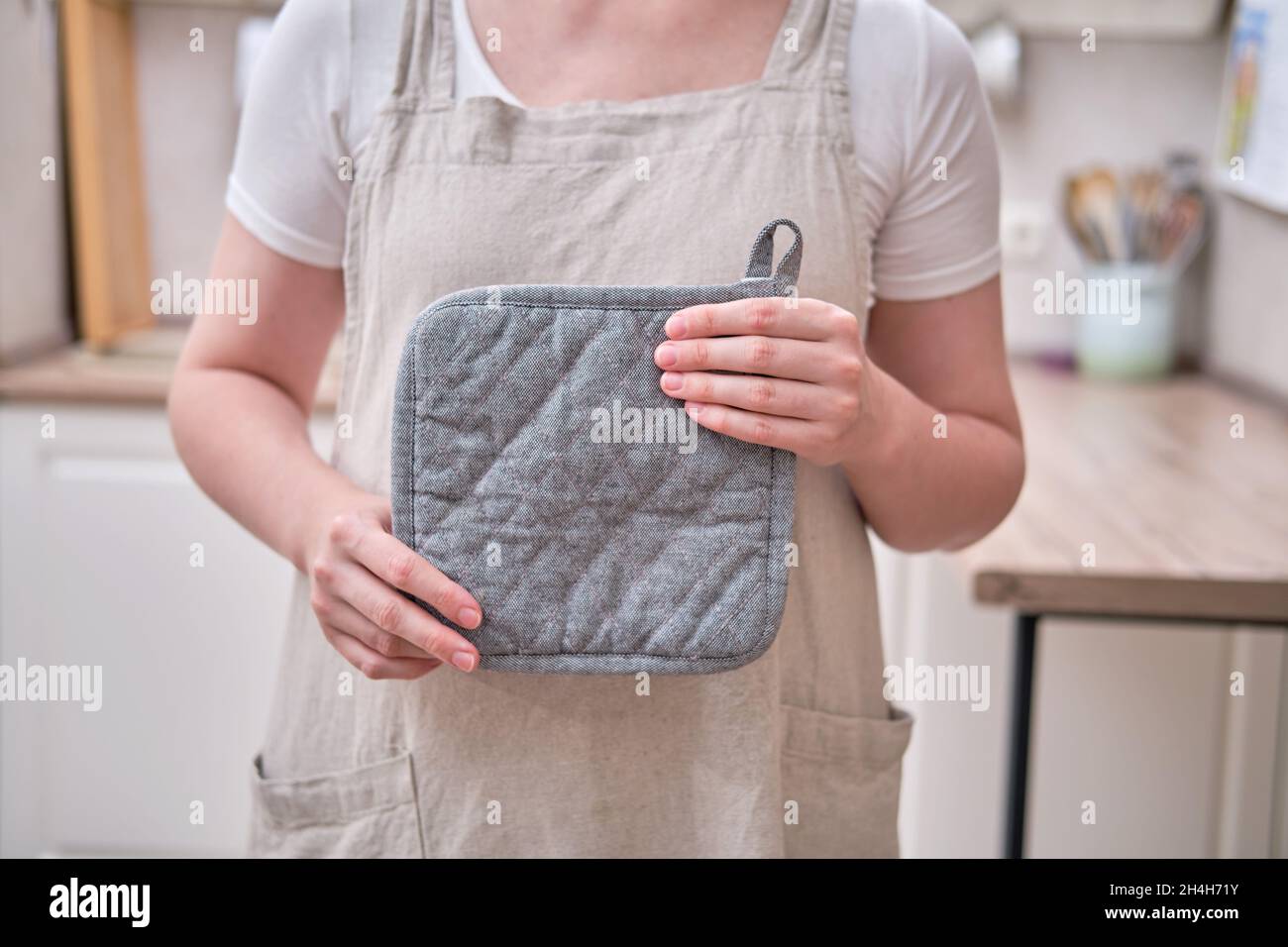 A potholder in the hands of a woman in the kitchen. Female hands ...