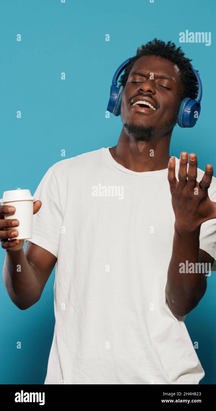 African american man using headphones to listen to music in studio ...