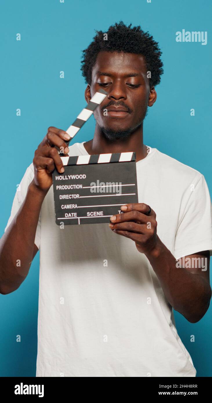 Portrait of man holding clapperboard to cut scenes in movie industry ...