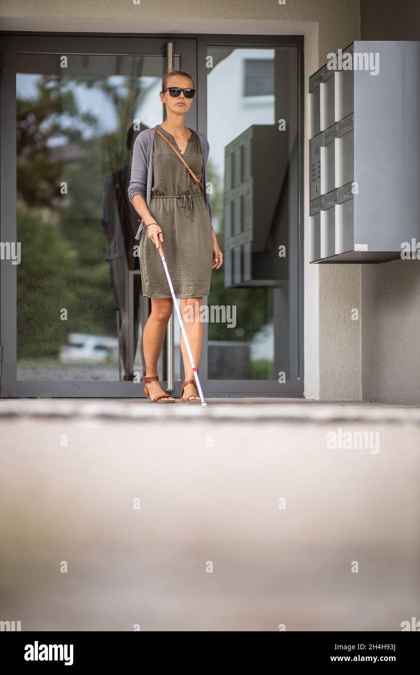 Young woman with impaired vision walking on city streets, using her ...