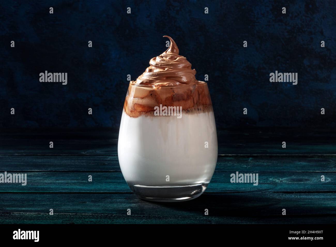 Dalgona cold coffee, side view on a dark background. Sweet Korean drink ...