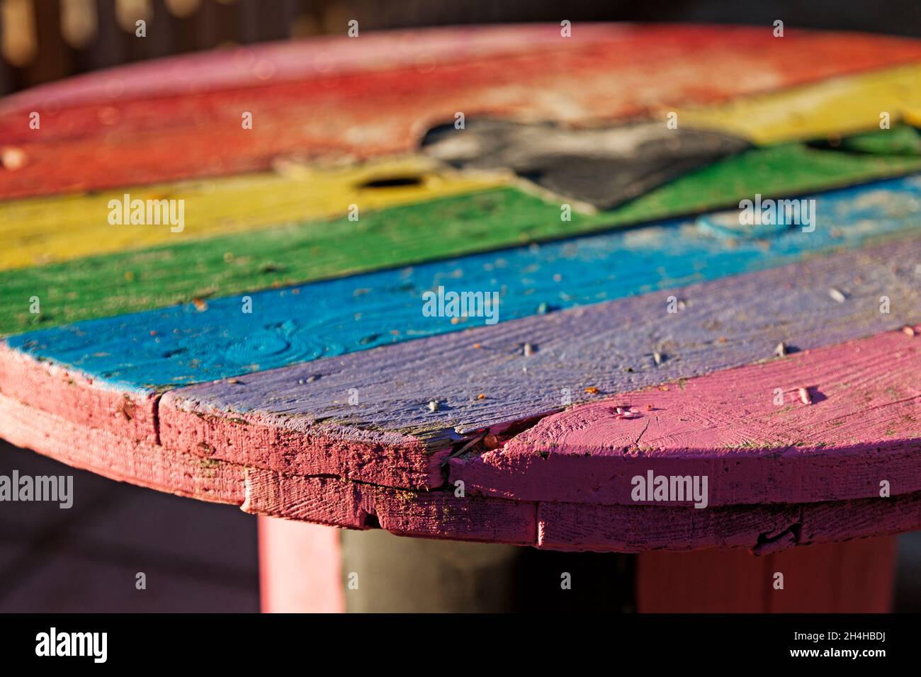 rainbow colored table made of an old wooden spool from construction ...