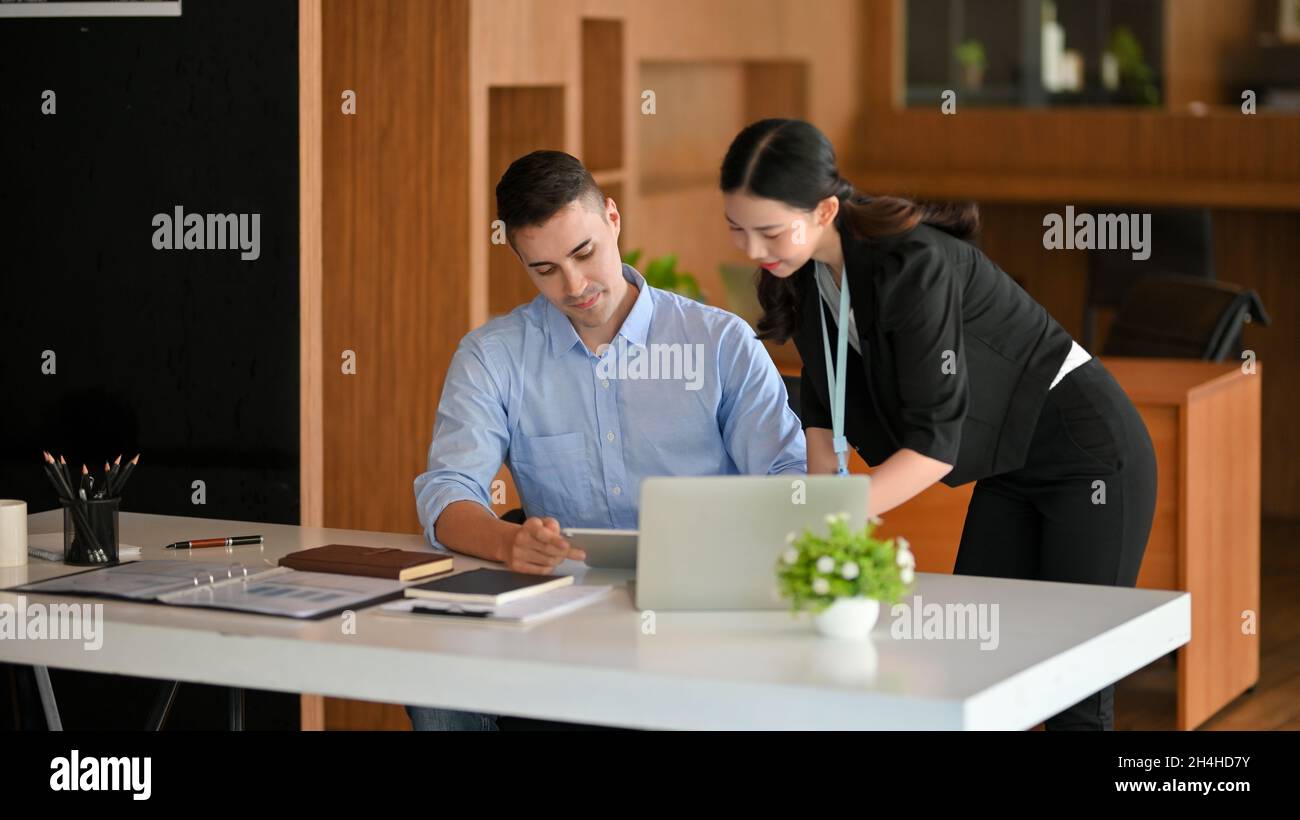 Asian female boss coaching and training works to her new caucasian male ...