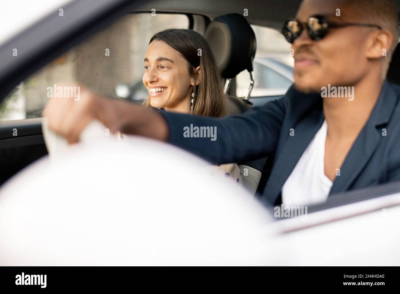 Happy multiracial couple driving at car together Stock Photo - Alamy