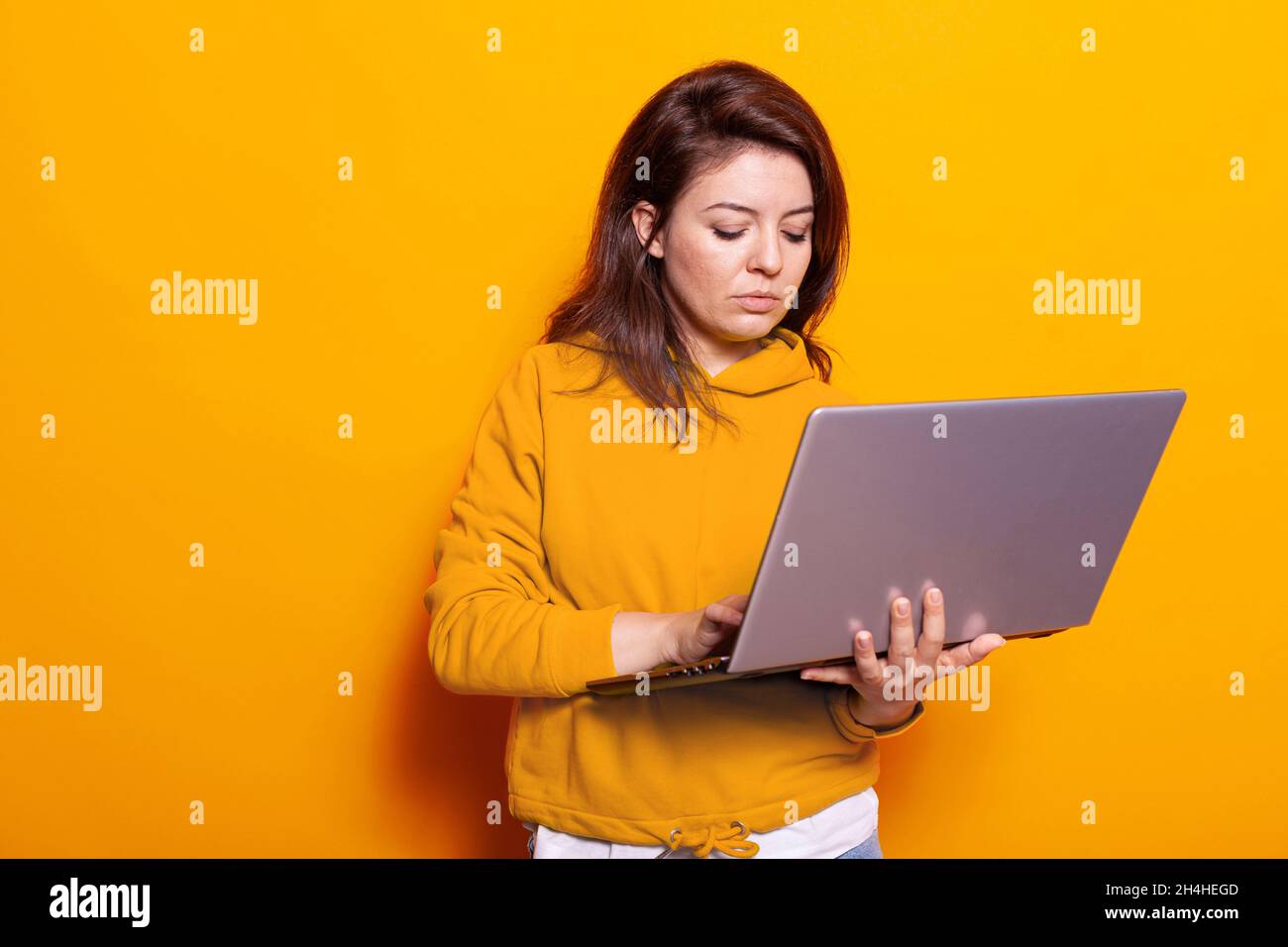 Modern person holding laptop to use technology on camera in studio ...