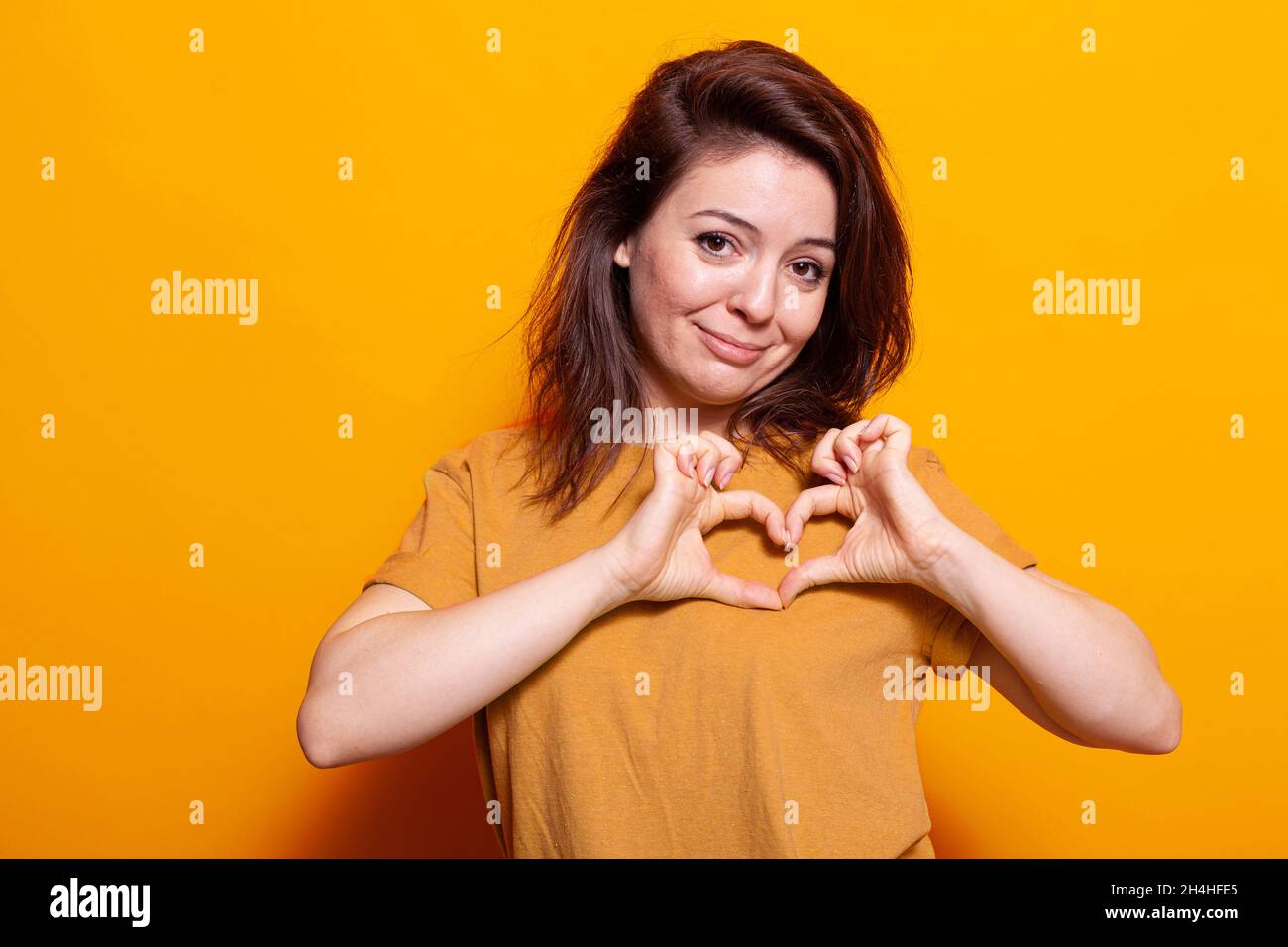 Caucasian woman showing heart shape with fingers at camera. Portrait of ...