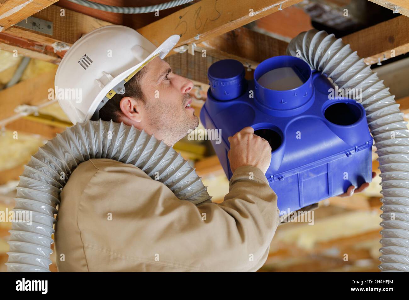 a tradesman installing ventilation system Stock Photo - Alamy