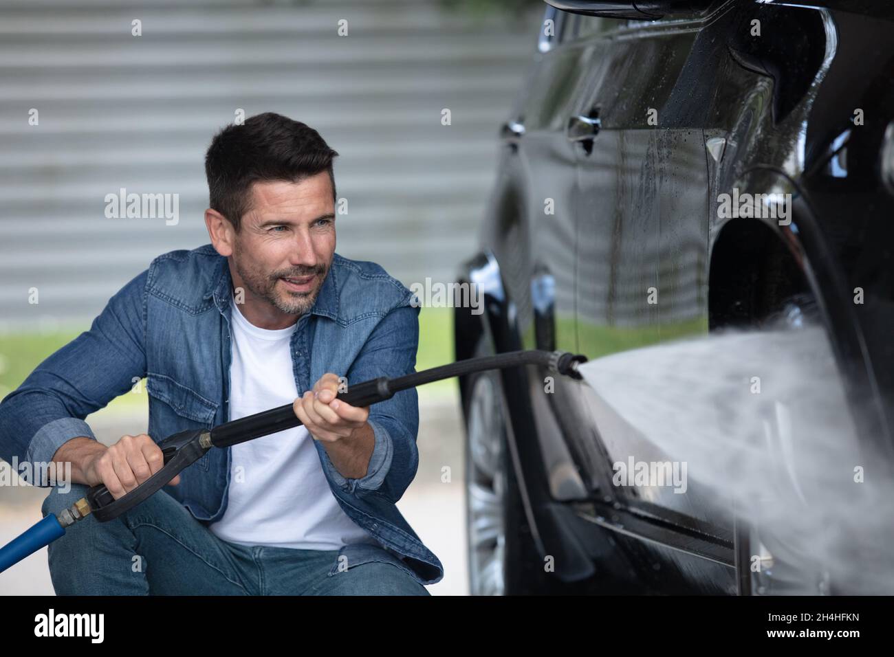 young man washing his car in a self service booth Stock Photo - Alamy