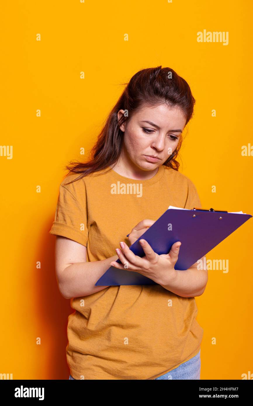 Young person taking notes on notebook files with pen in studio ...