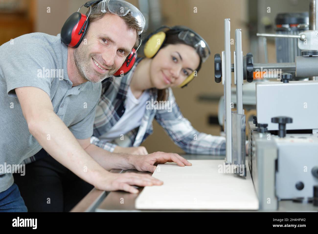 carpenter showing apprentice how to use sawing machine Stock Photo - Alamy