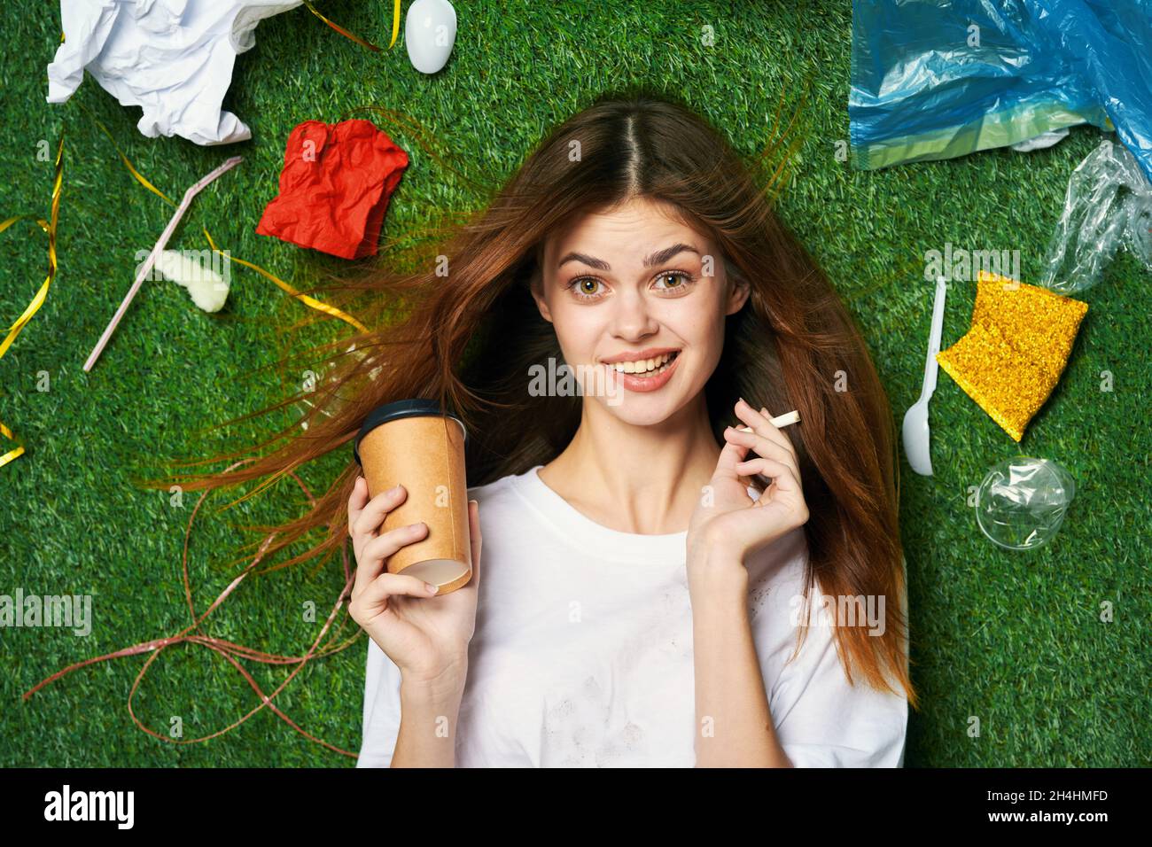 woman lies on the grass in nature and scattered plastic around ...