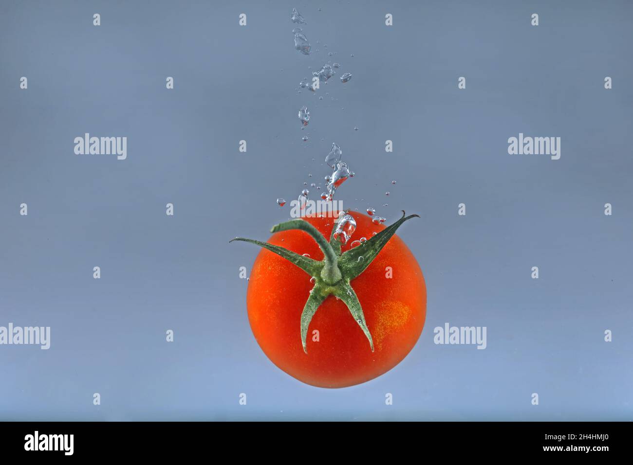Fresh cherry tomato falling into clear water Stock Photo - Alamy
