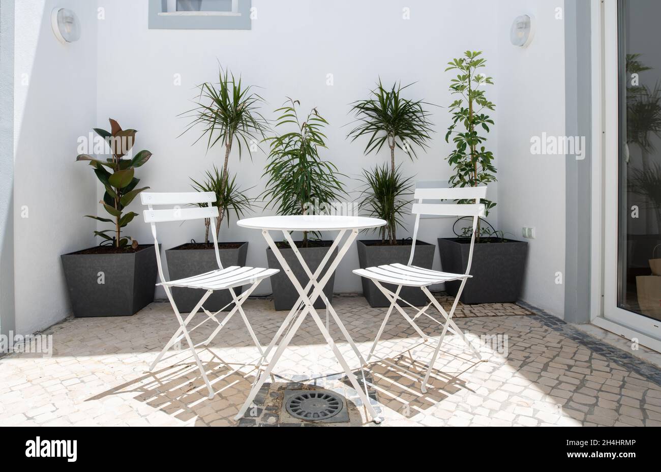Internal patio courtyard with white metal table and chairs and planters ...