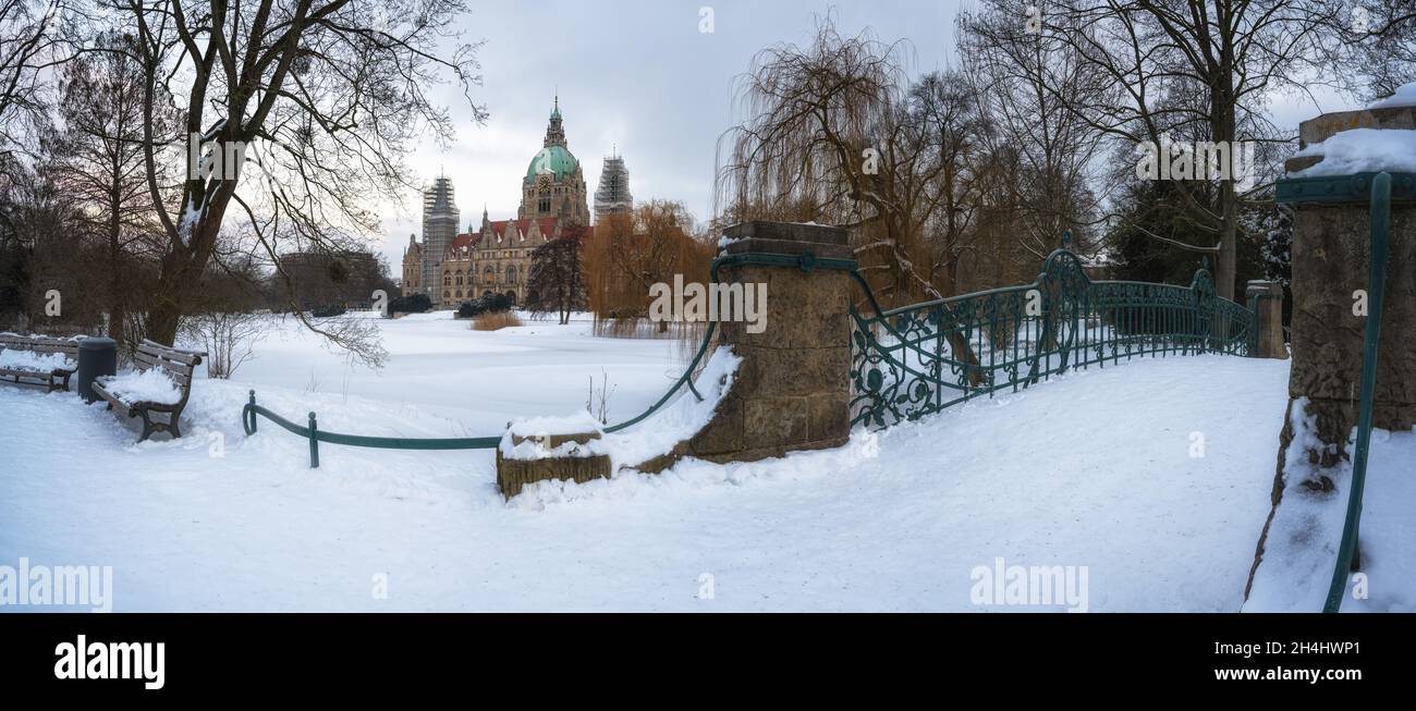 New town hall of Hanover in winter with snow on the pond and branches ...