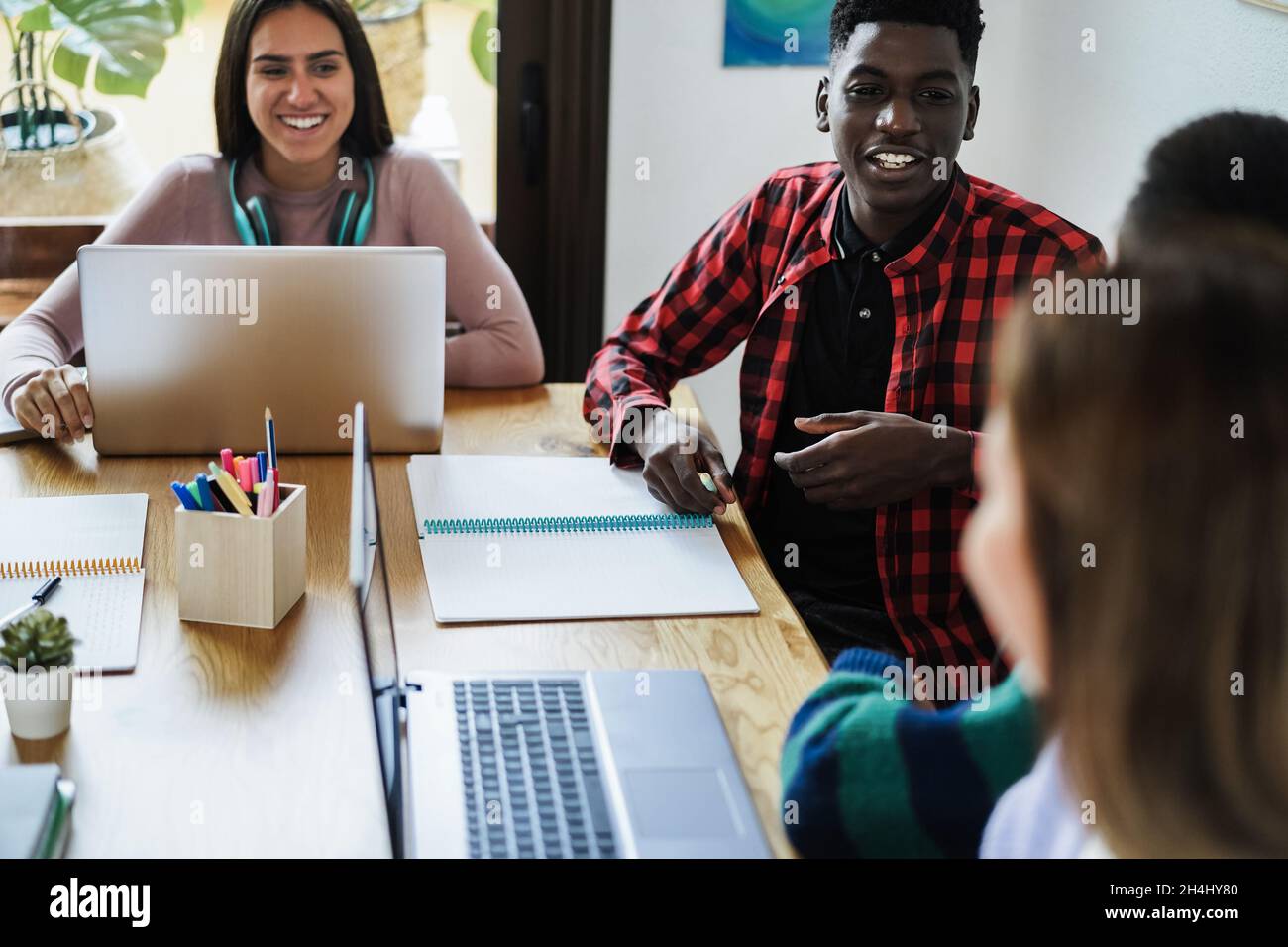 Multiracial students using laptop computers while studying together at ...