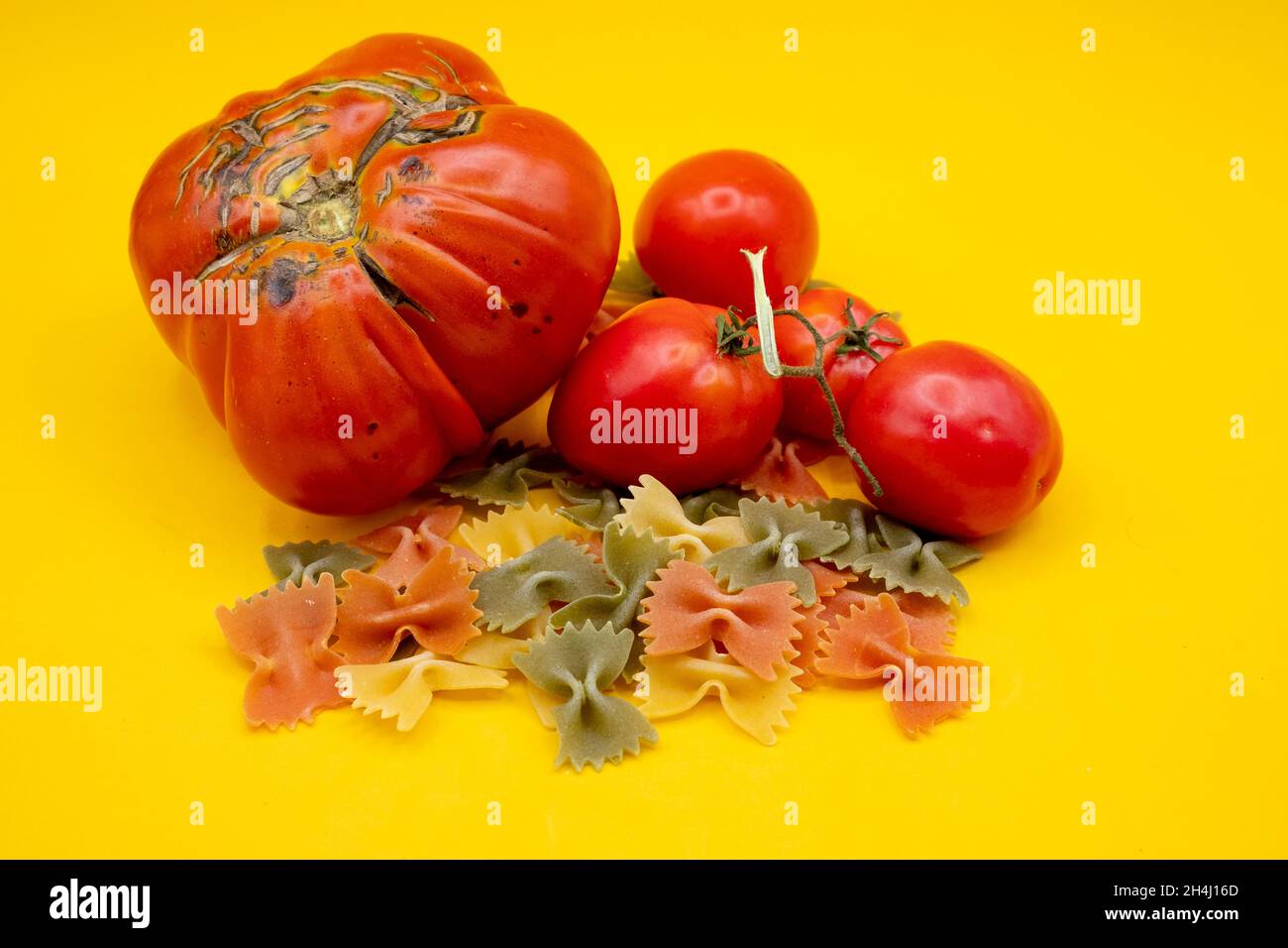 organically grown tomatoes and paste on a yellow background Stock Photo - Alamy