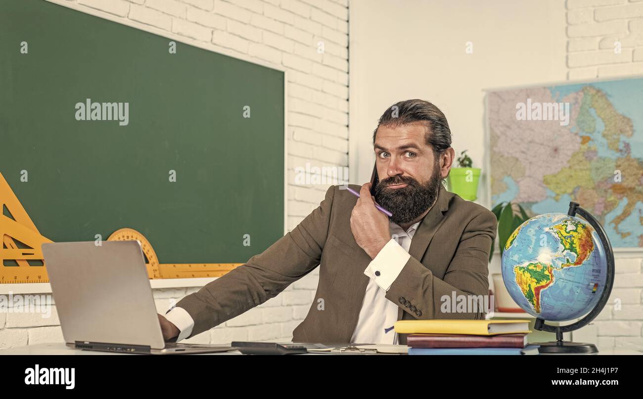 Smiling teacher has phone conversation in classroom, school online ...