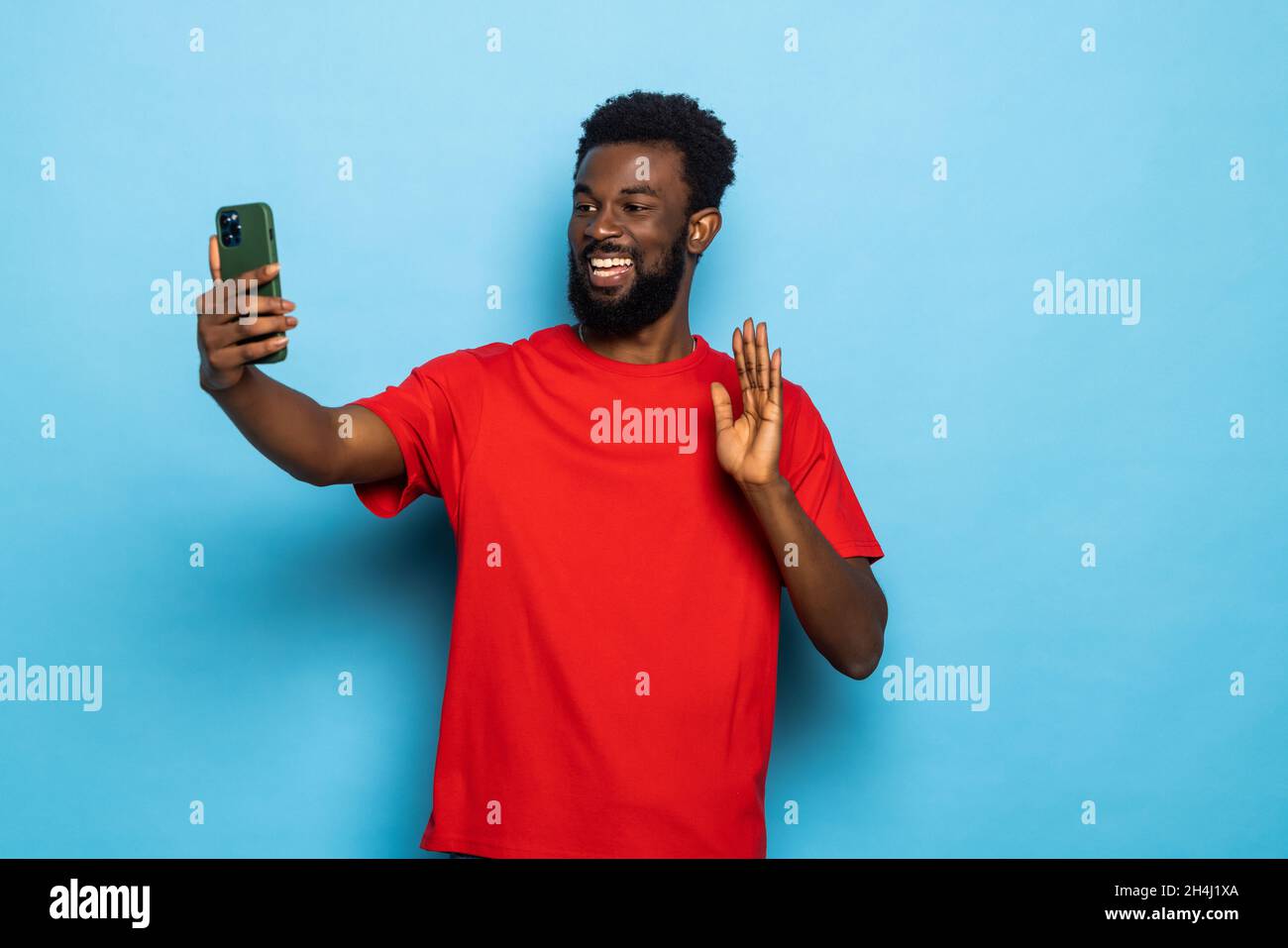 Portrait of a young afro american man looking at mobile phone and ...
