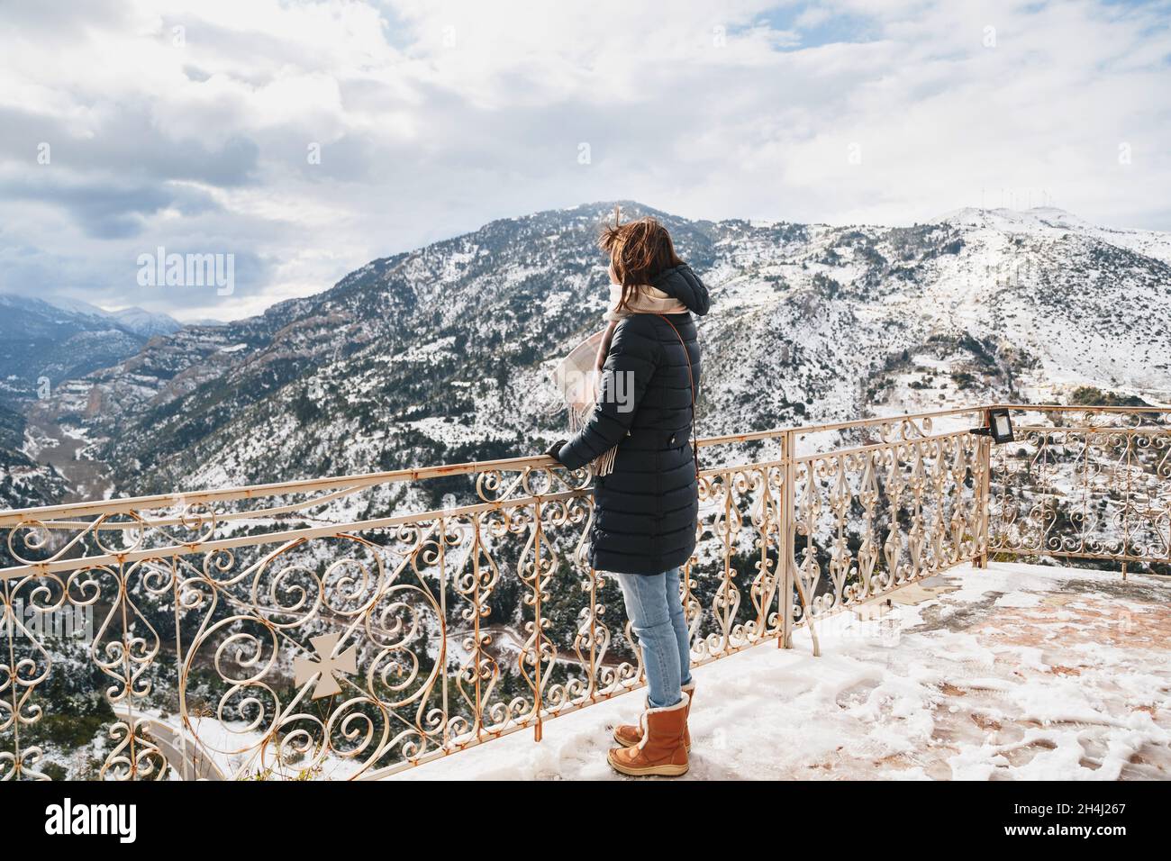 Back view of young woman standing at mountain top observation deck over ...