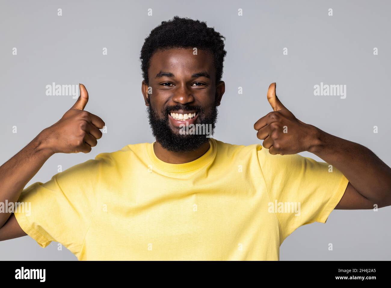 Young african man with thumbs up on gray background Stock Photo - Alamy