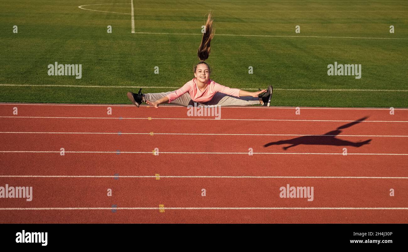 teen girl jumping in split outdoor on racing track stadium, energy ...