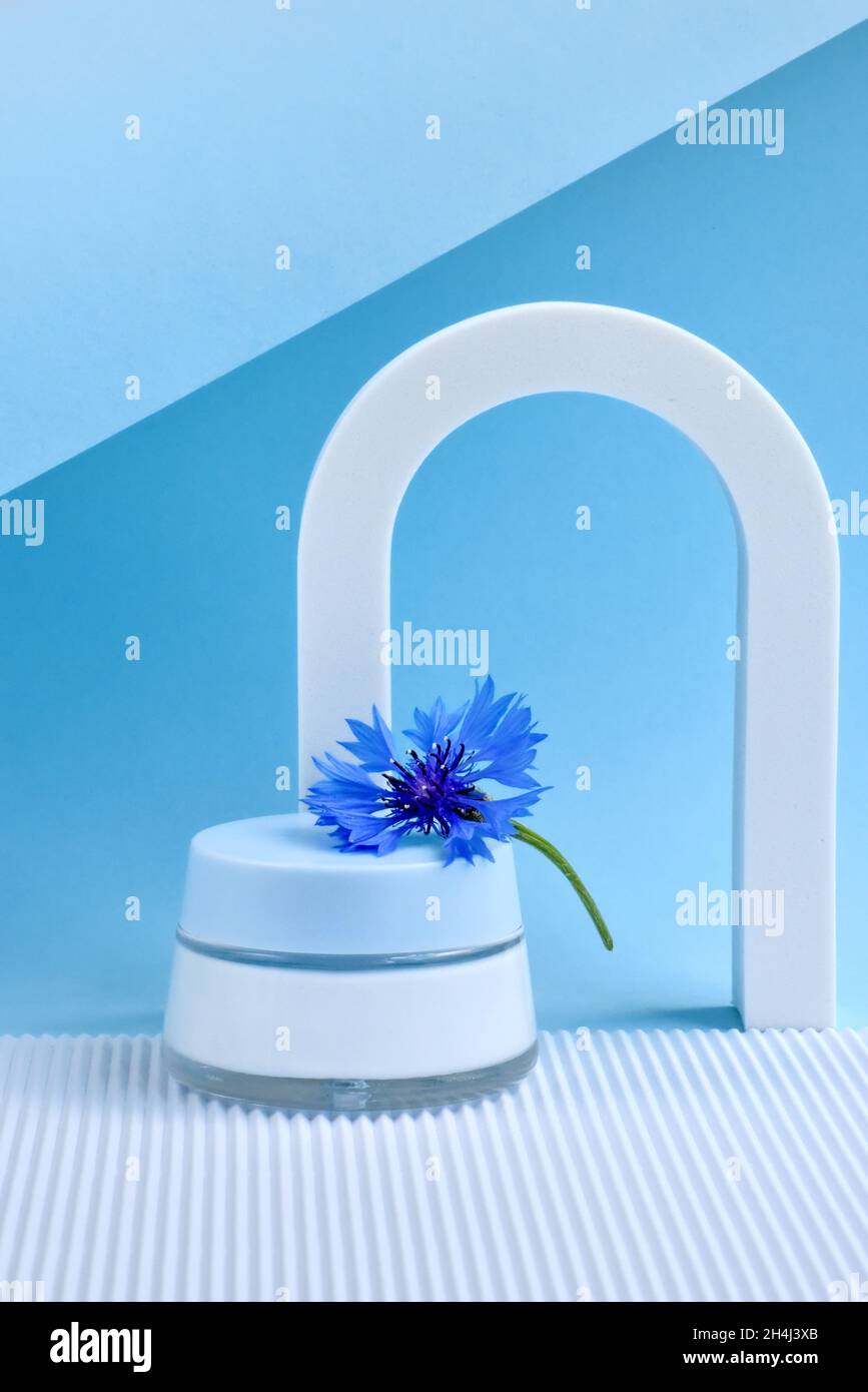 Cosmetic cream with cornflower on a blue background. Composition with ...