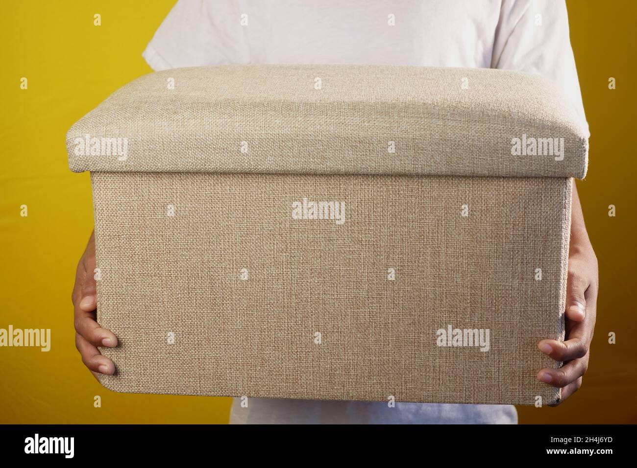 young man hand hold a box against yellow background Stock Photo - Alamy