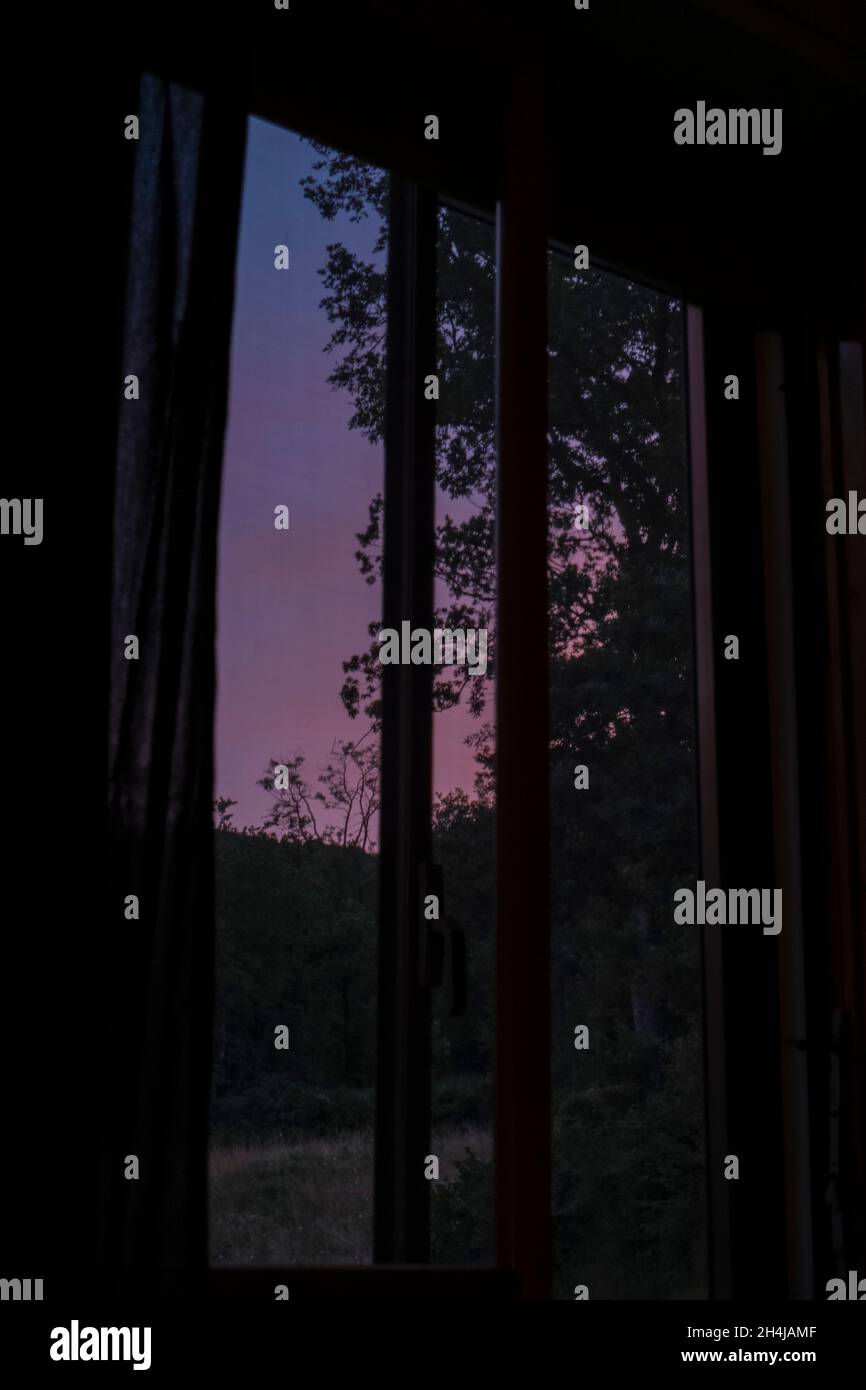 window view from a room to an evening sunset sky and trees. Indoor view ...