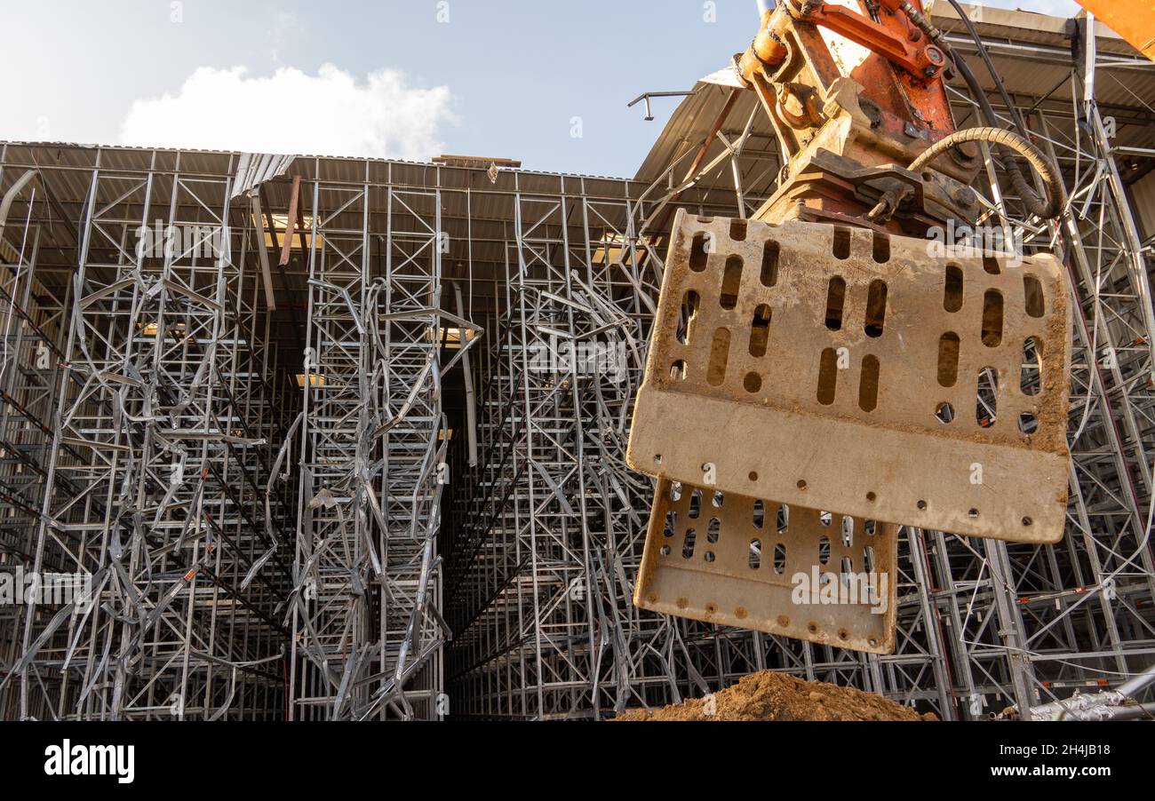 excavator bucket in front of the ruin of a partially demolished high ...