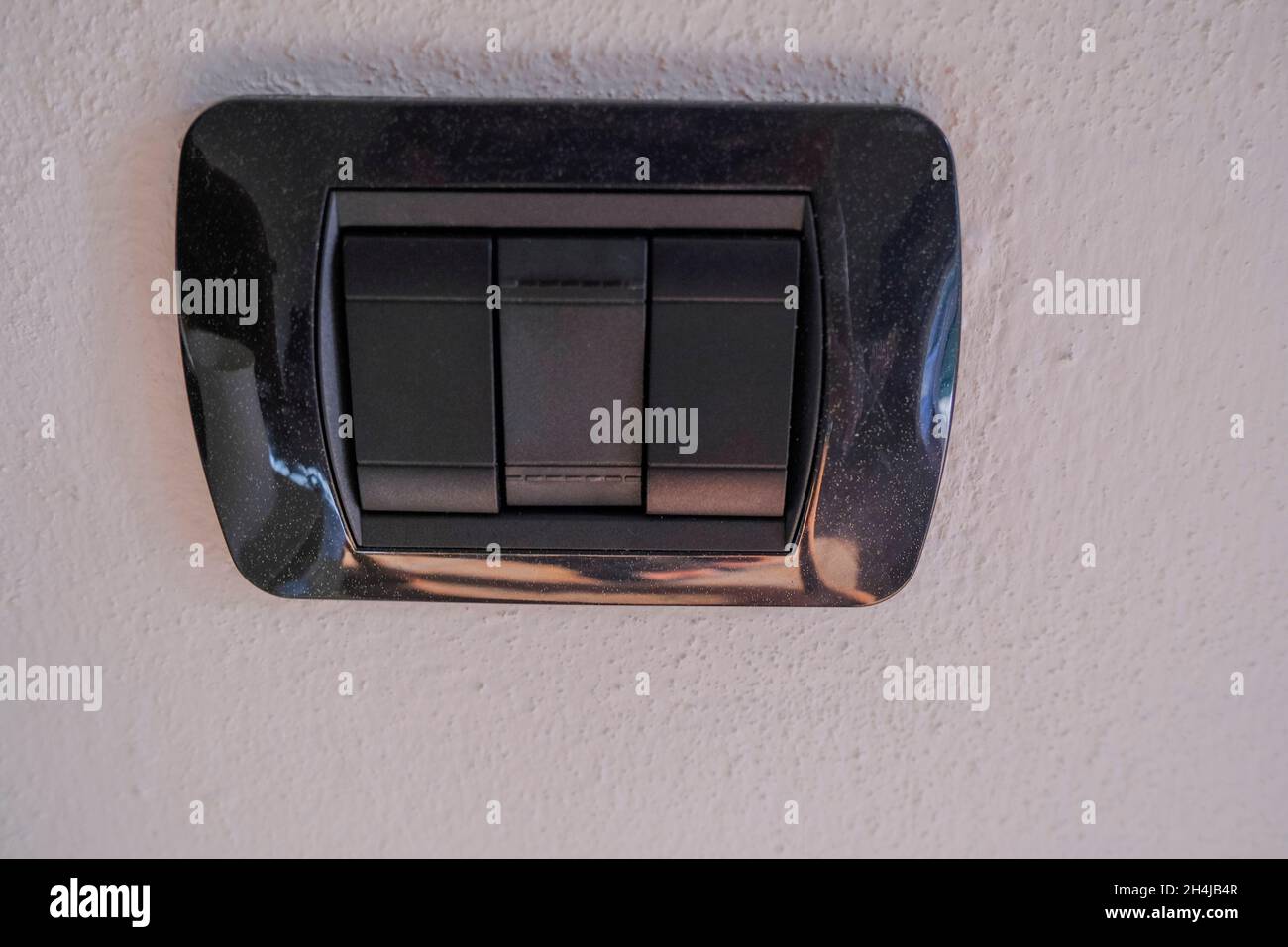 Black European switch close-up on the white wall. Electricity equipment ...