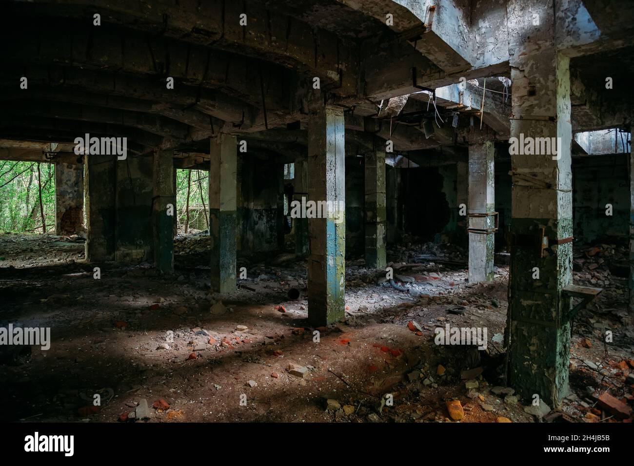 Old abandoned ruined industrial building overgrown by plants and trees ...