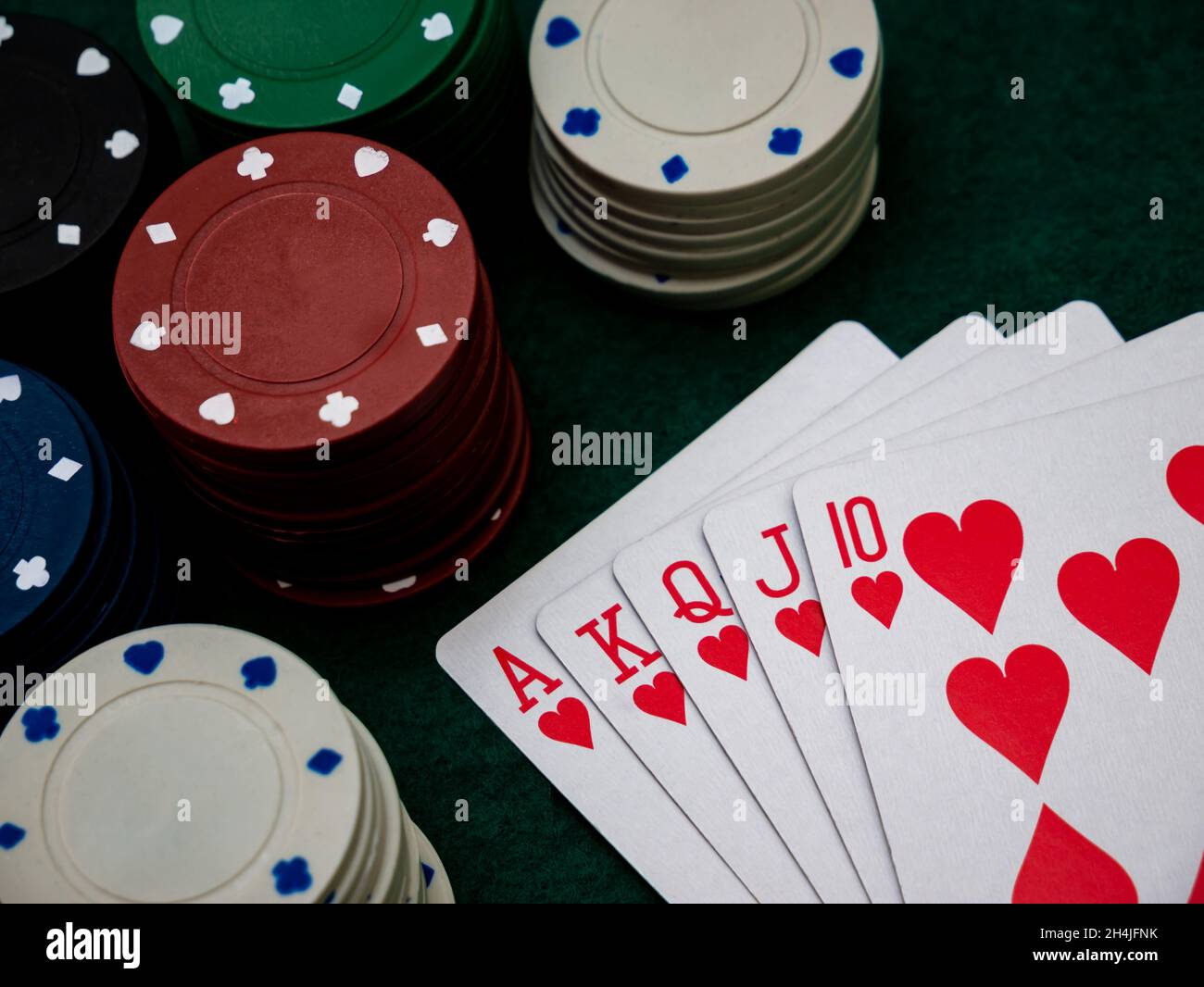 Royal straight flush poker cards with stack of poker chips on a green ...