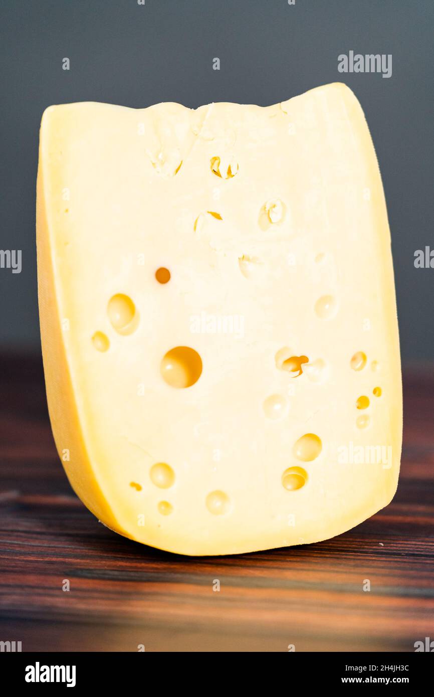 Large wedge of semi soft part-skim swiss cheese on a dark wooden ...