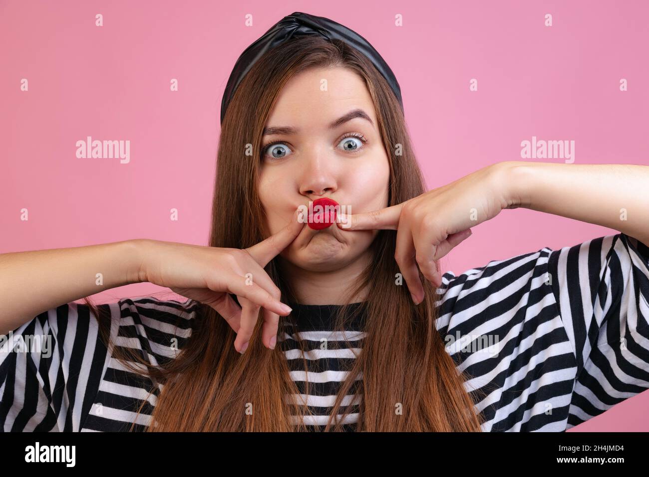 Portrait of young beautiful girl making faces isolated on light pink ...
