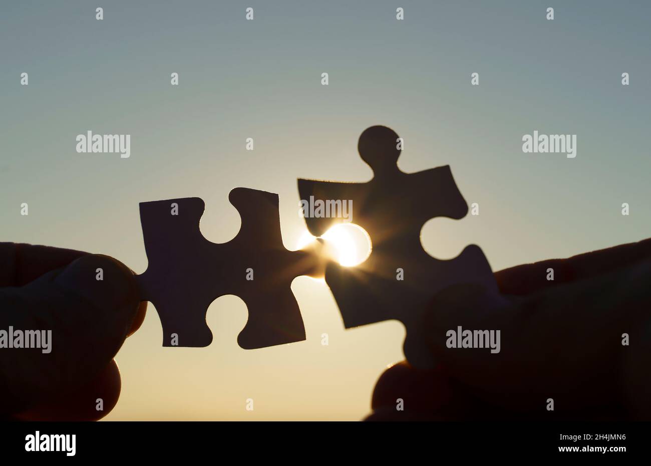 Puzzle pieces are connected. Puzzle pieces in hand on a sunny sky ...