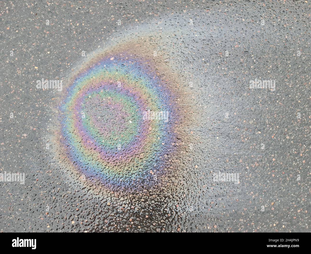 Rainbow stain on wet asphalt from machine oil closeup background Stock ...