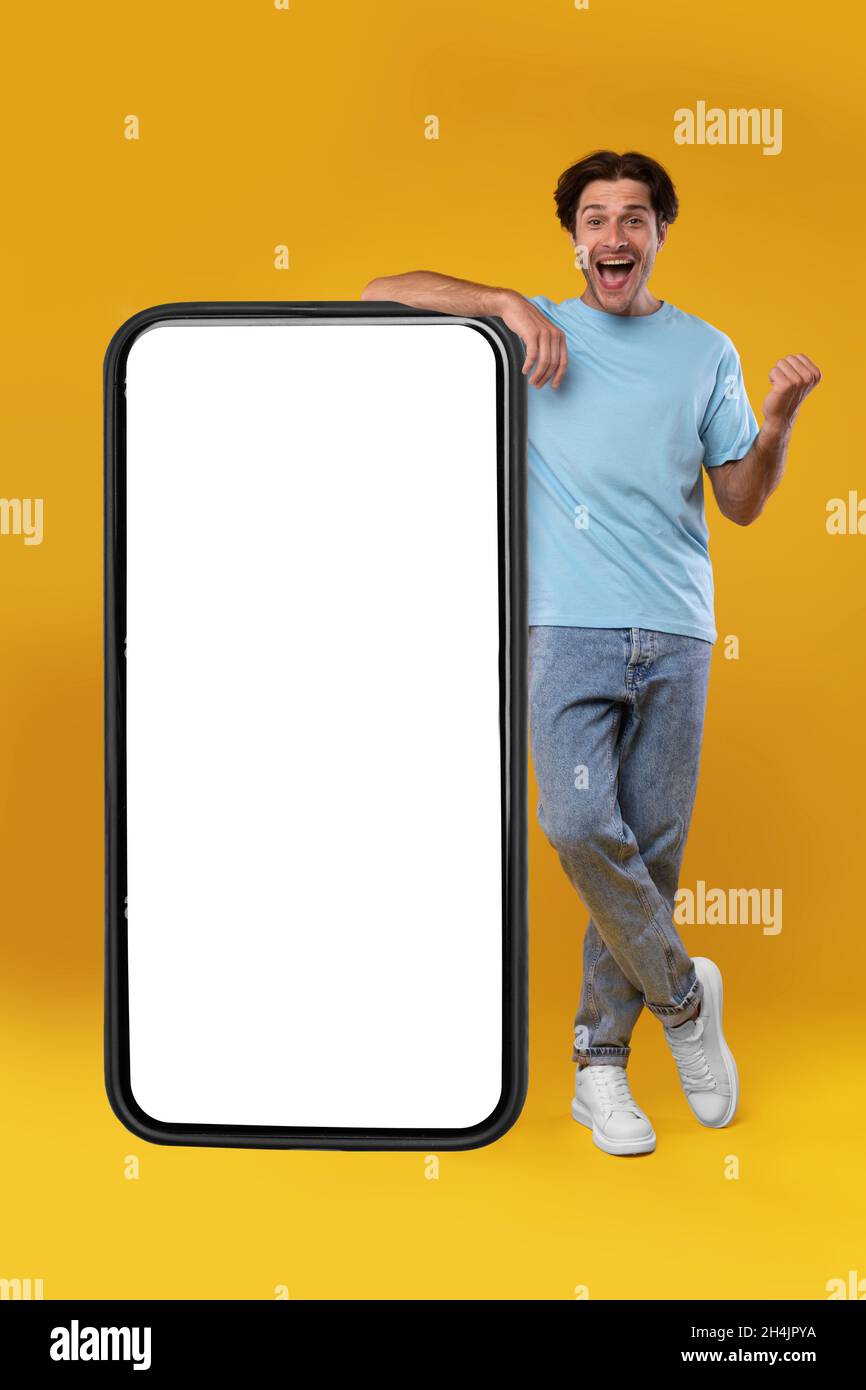 Big Luck And Win. Excited Male Leaning On Big Cell Phone With Empty ...