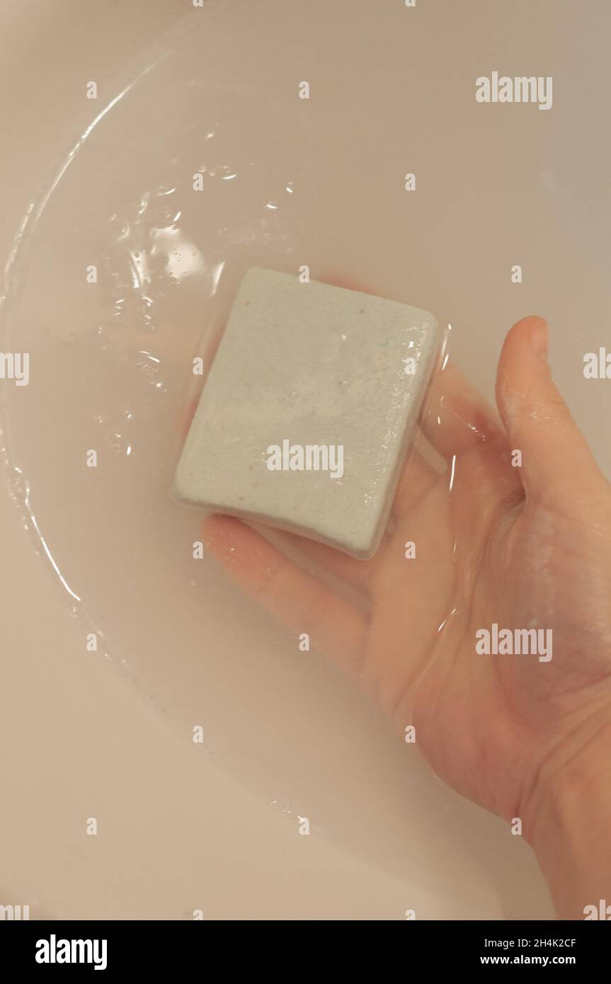 Overhead view of a wet soapy hand holding a bar of soap over a sink ...