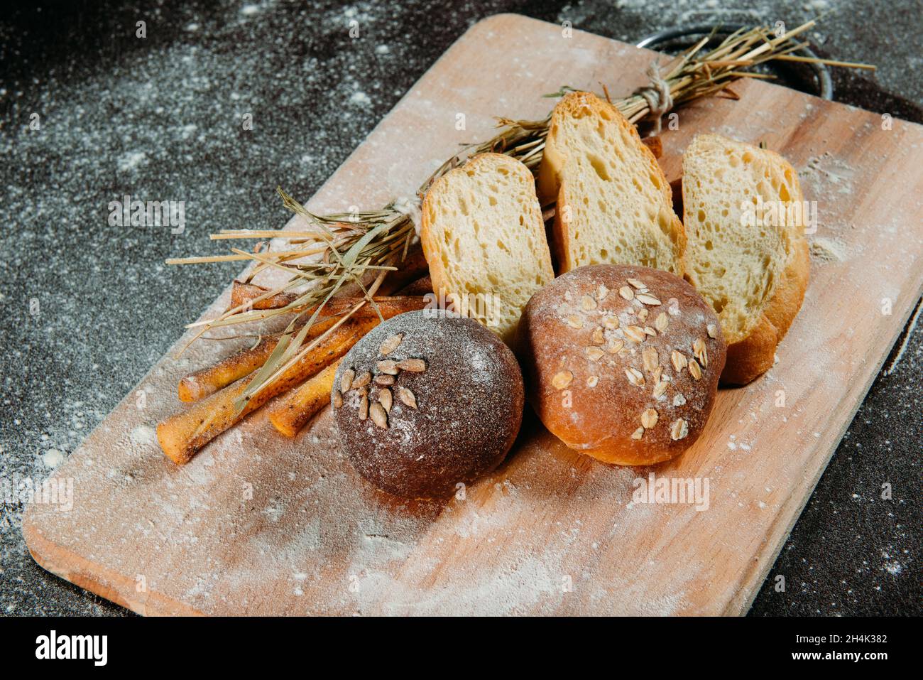 Assorted bread rolls, slices of bread and breadsticks on a chopping ...