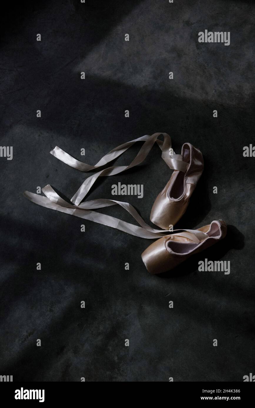 Overhead view of a pair of pink ballet shoes on the floor in sunlight ...