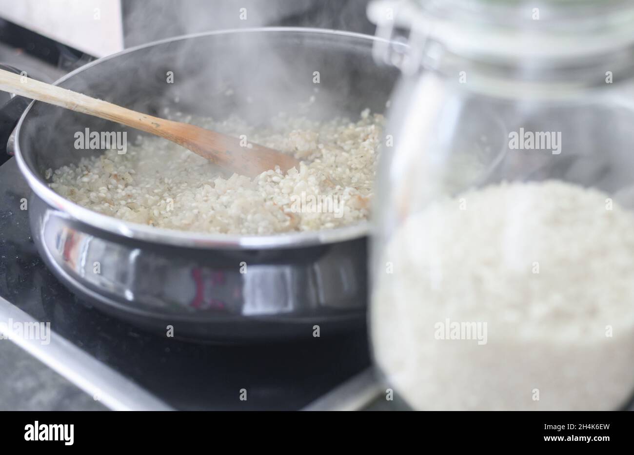 SCENE OF RICE COOKING IN CASSEROLE WITH A JAR NEXT TO IT Stock Photo ...