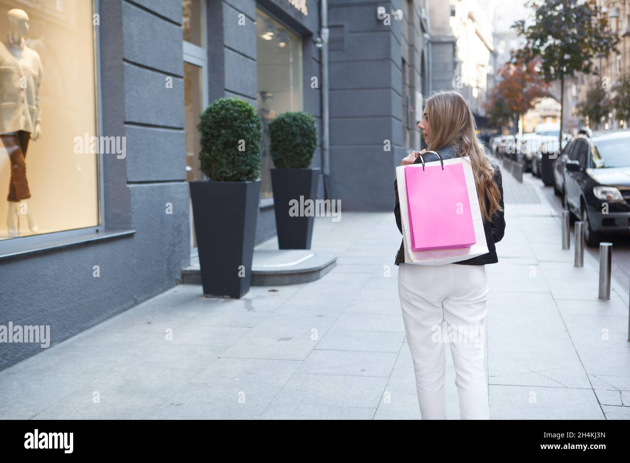 Woman walking past fashion store in the city, looking at retail display ...