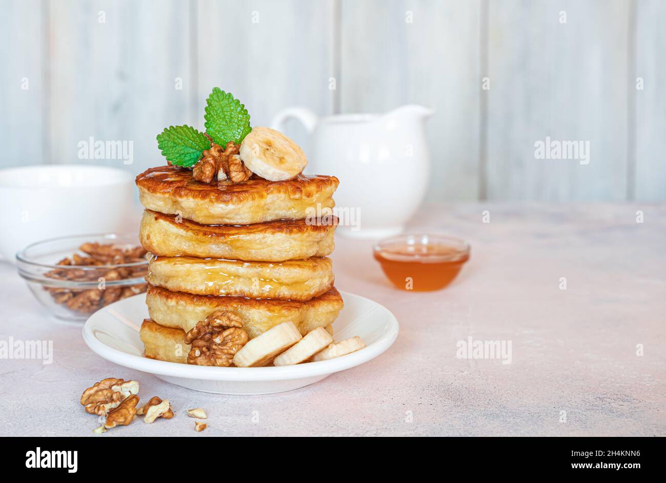 Homemade pancakes with nuts, honey and banana on a light background ...