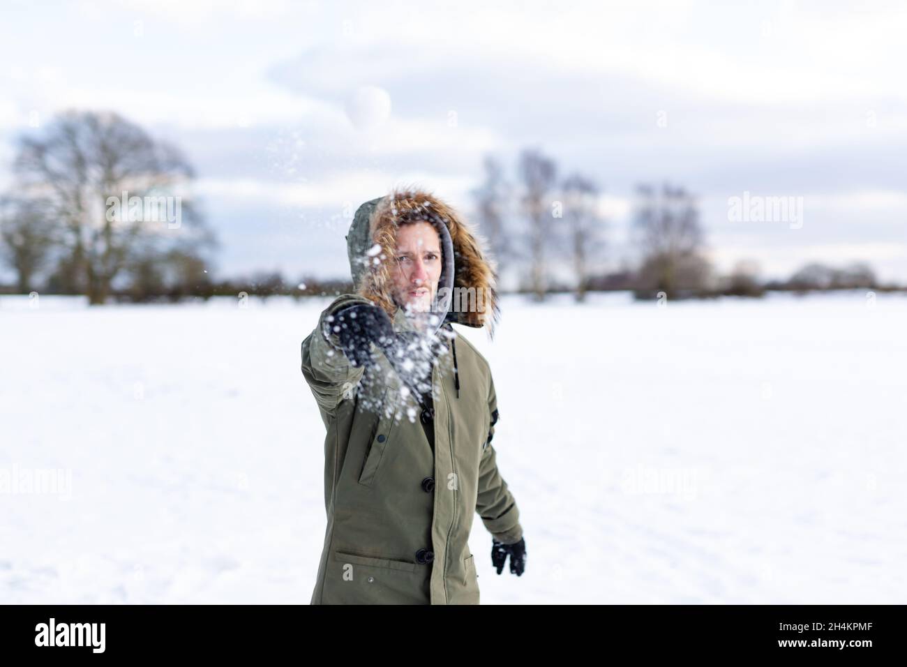 A determined looking young man throwing a snowball towards the camera ...