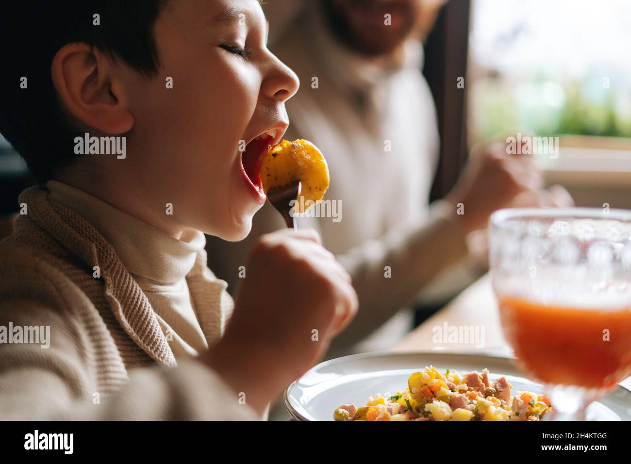Close-up face of pertty child kid boy eating fried potatoes sitting at ...