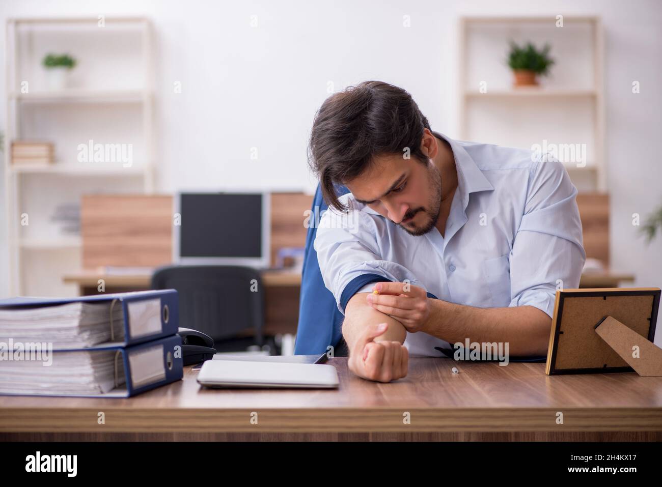 Young male drug addicted employee in the office Stock Photo - Alamy